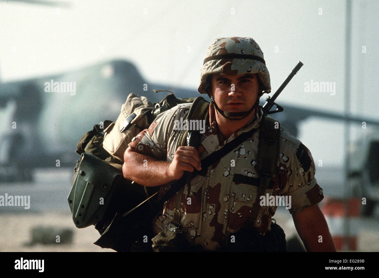 A soldier carries his gear after arriving in Saudi Arabia during ...