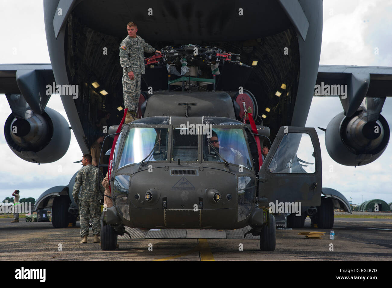 Service members unload a U.S. Army UH-60 Black Hawk from a U.S. Air ...