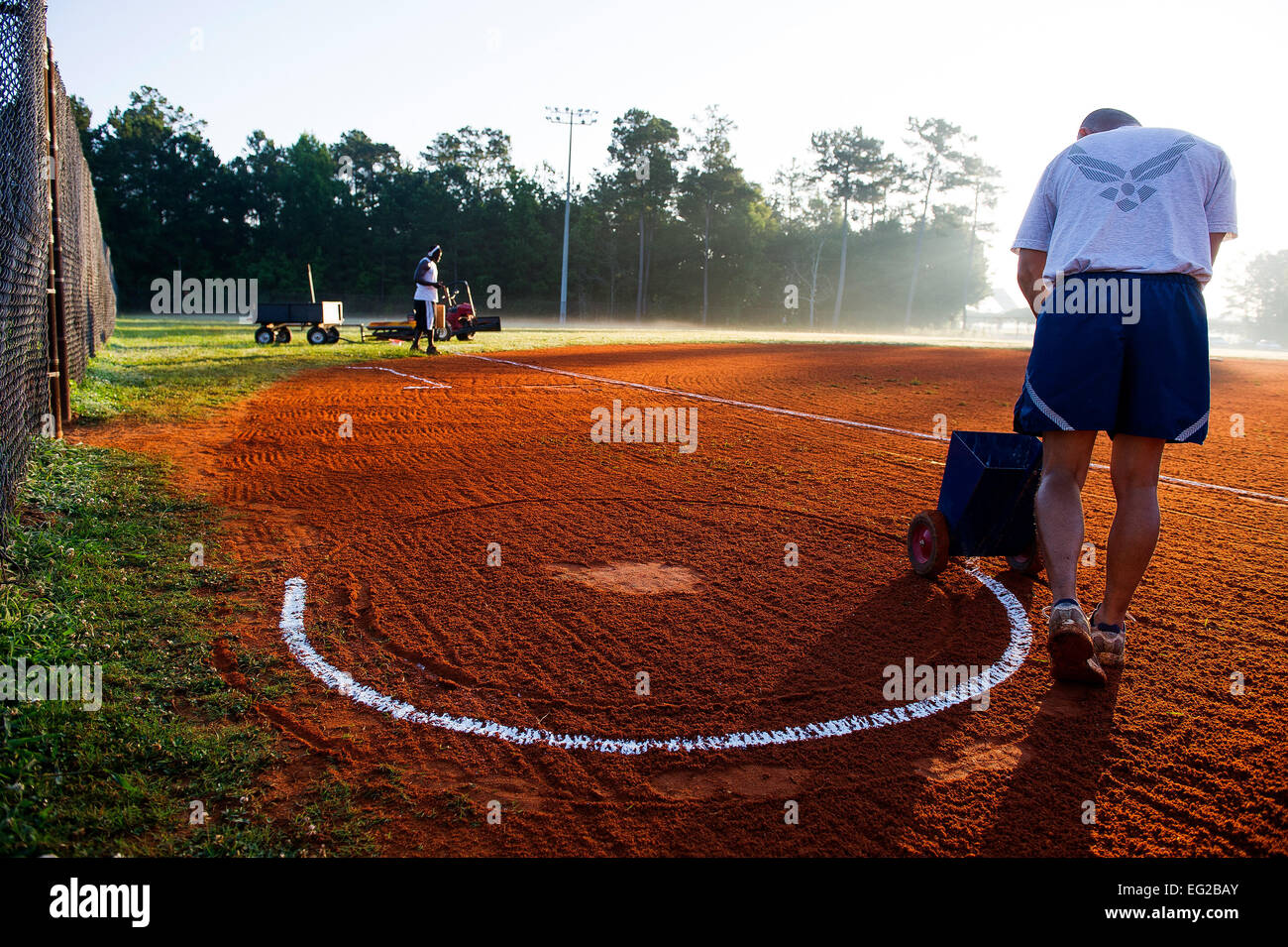 Staff Sgt. Lakan Ello uses a chalk dispenser to make an on-deck circle ...