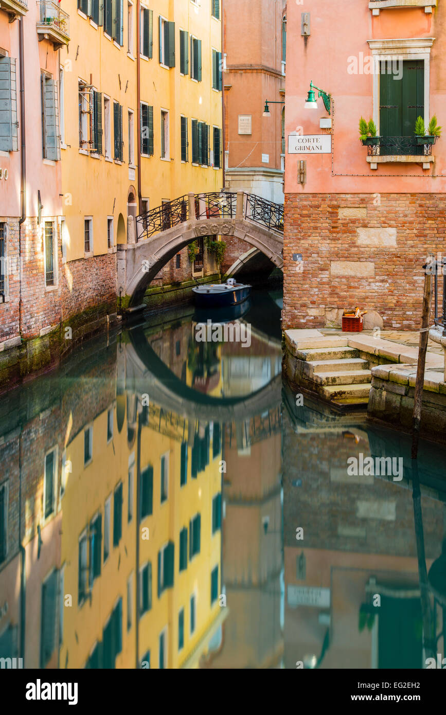 Picturesque view of a canal with buildings and stone bridge reflected ...
