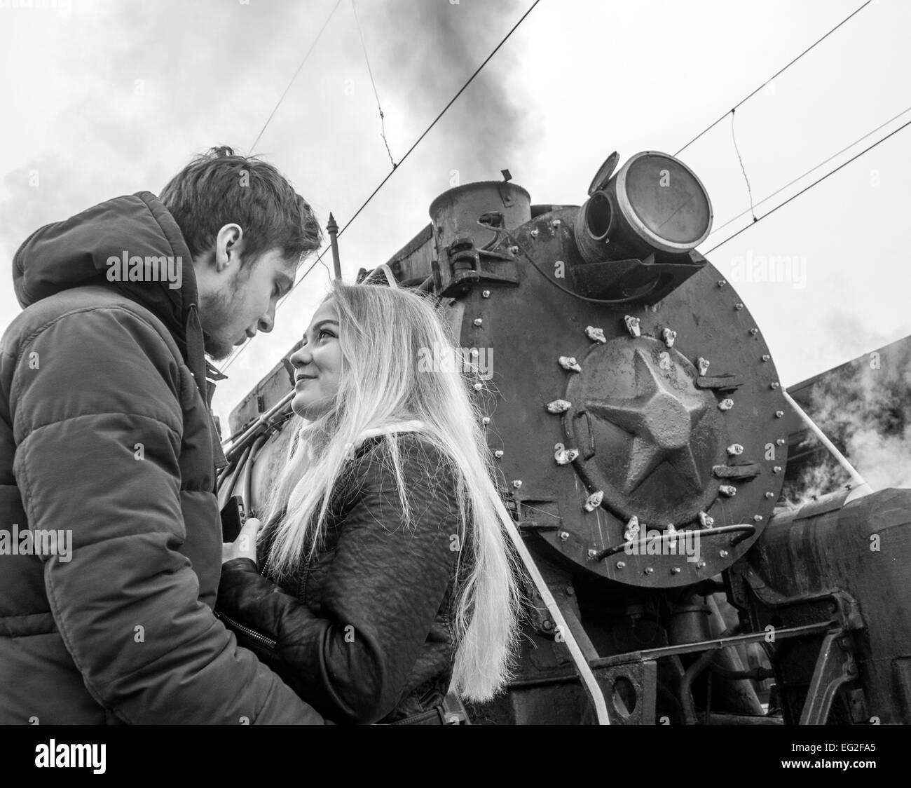 Young couple kissing on the background of an old steam locomotive ...