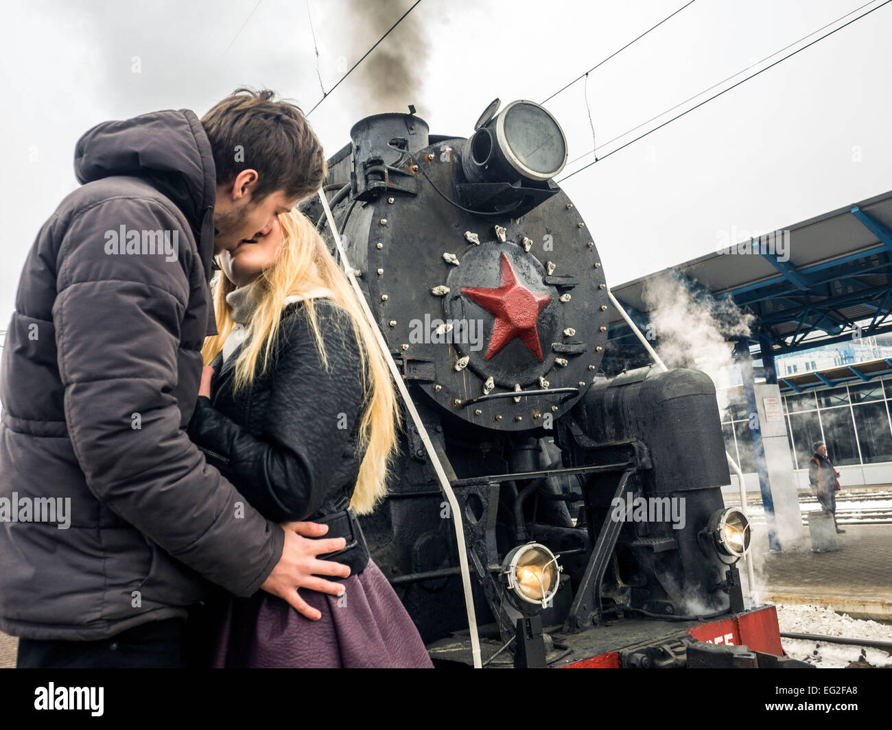 Young couple kissing on the background of an old steam locomotive ...