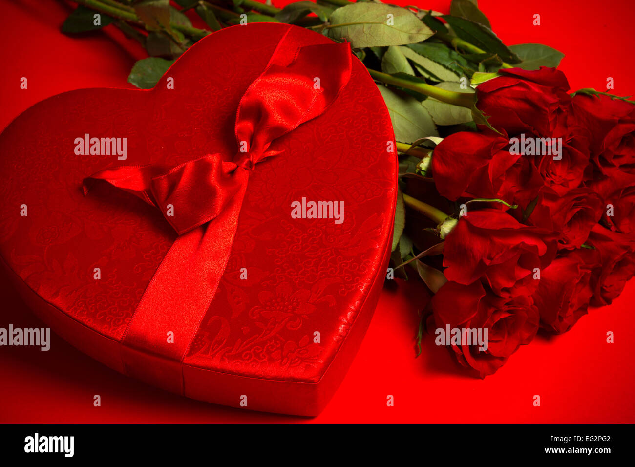 Long stem red roses and box of candy on a red background. Valentine's ...