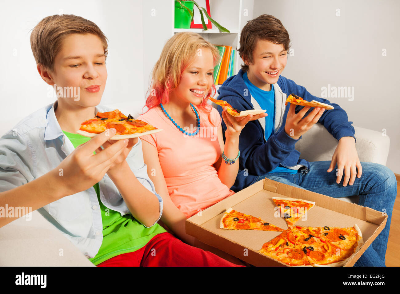 Teenagers holding pizza pieces and eating Stock Photo - Alamy
