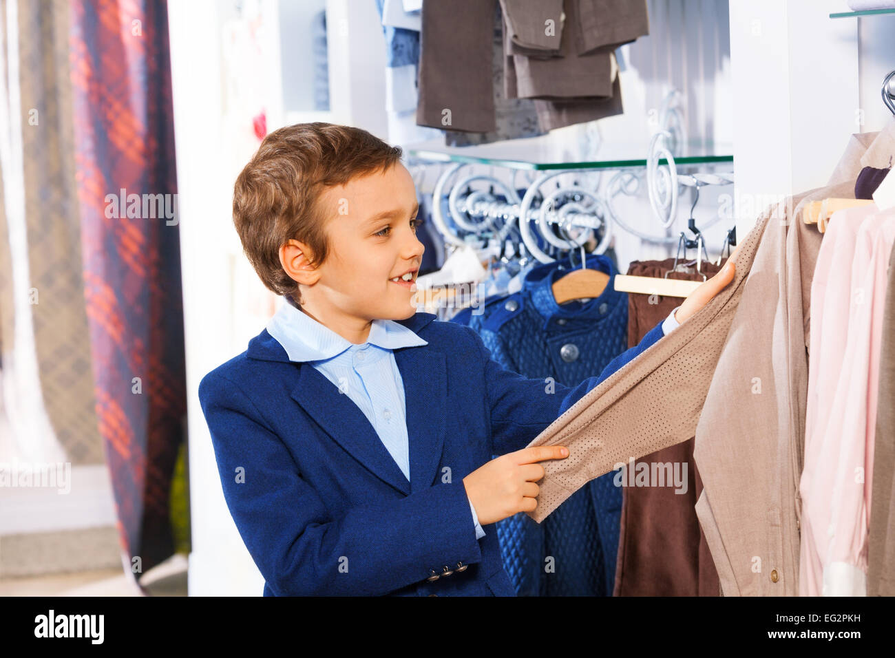 Cute smiling boy stands near clothes and choosing Stock Photo - Alamy