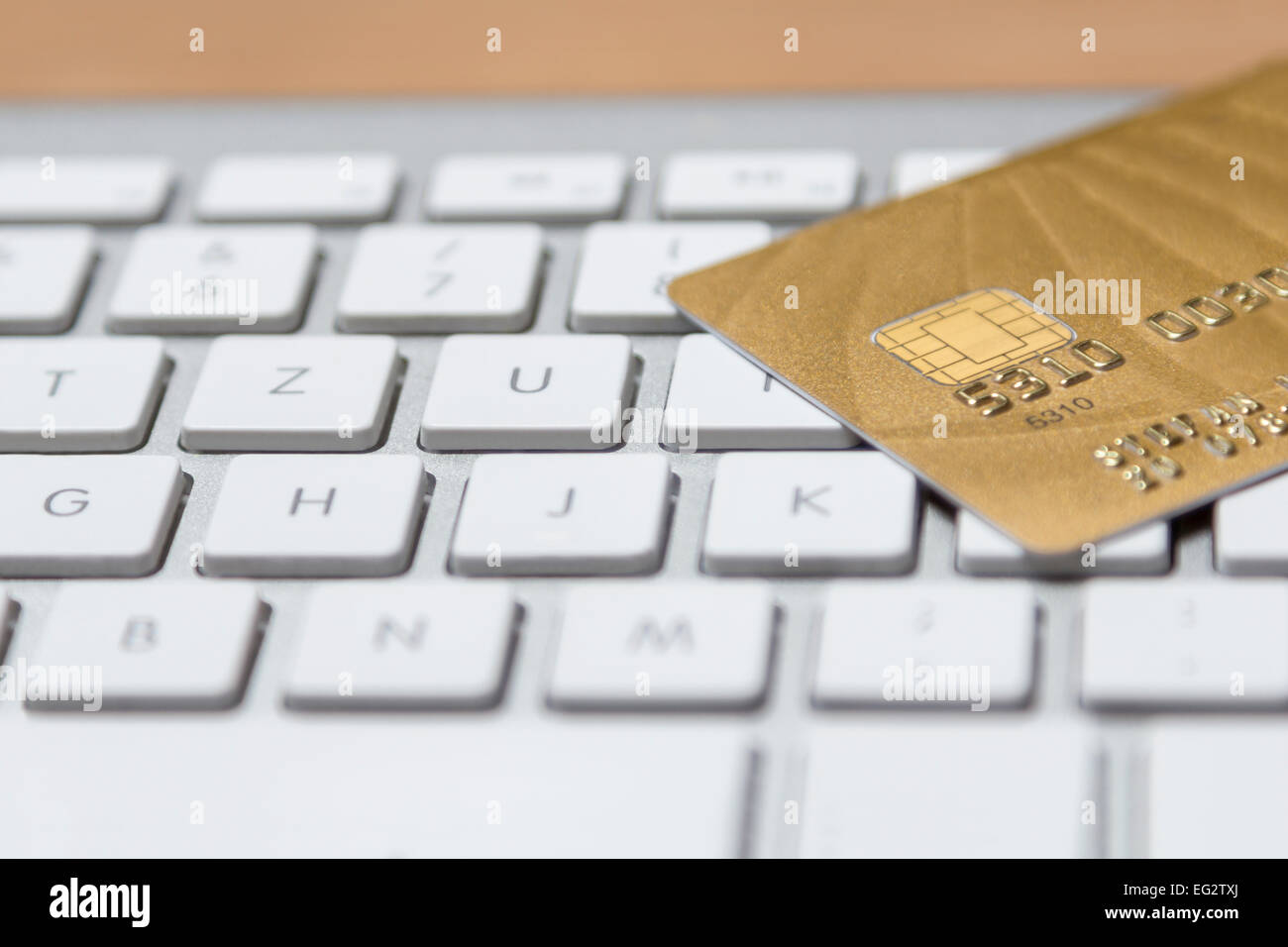 a golden credit card on a modern silver keyboard Stock Photo - Alamy