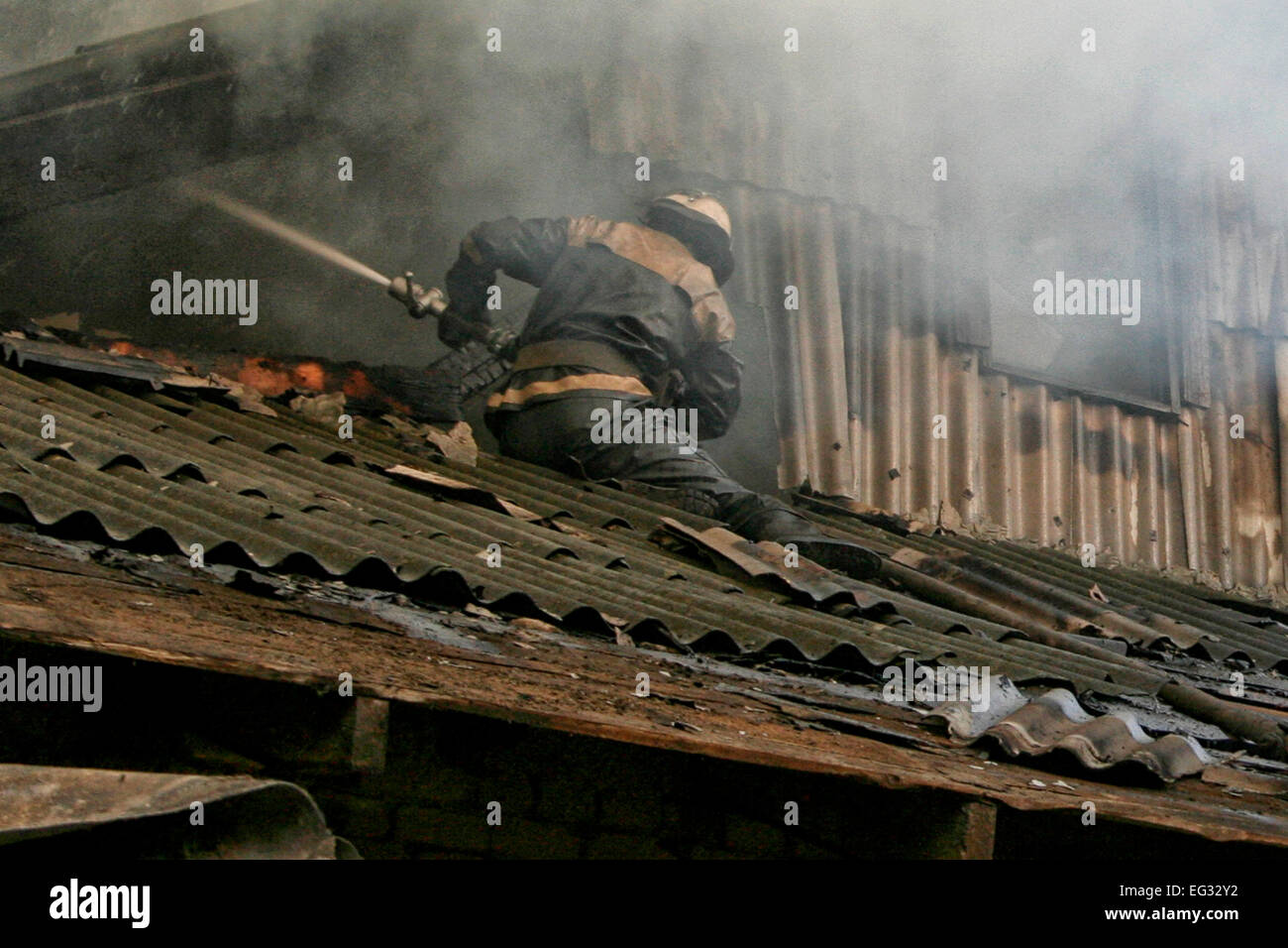 Smoldering remains of a ghetto house with a fireman spraying water ...