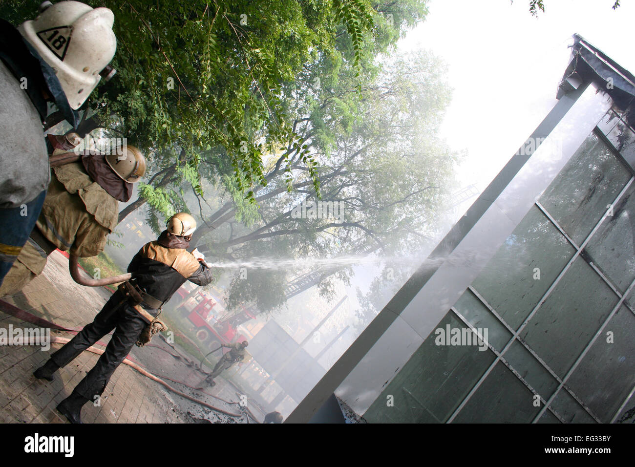 Smoldering remains of a ghetto house with a fireman spraying water ...