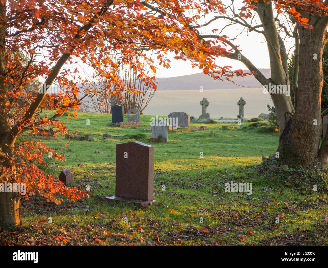 The golden light of the setting sun shining upon a graveyard in England ...