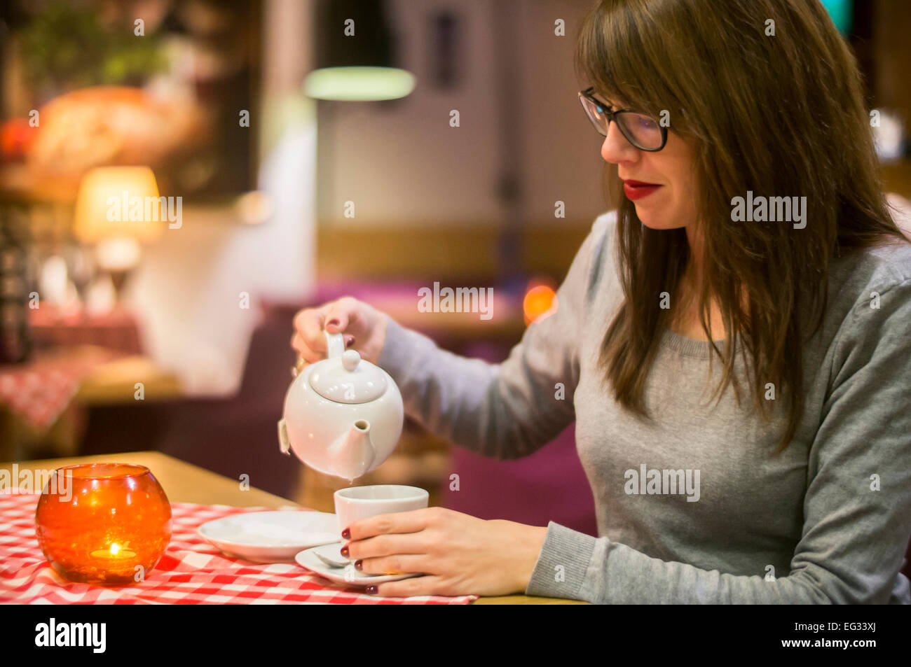 Beautiful young woman enjoying a hot drink with friends in a cosy cafe ...