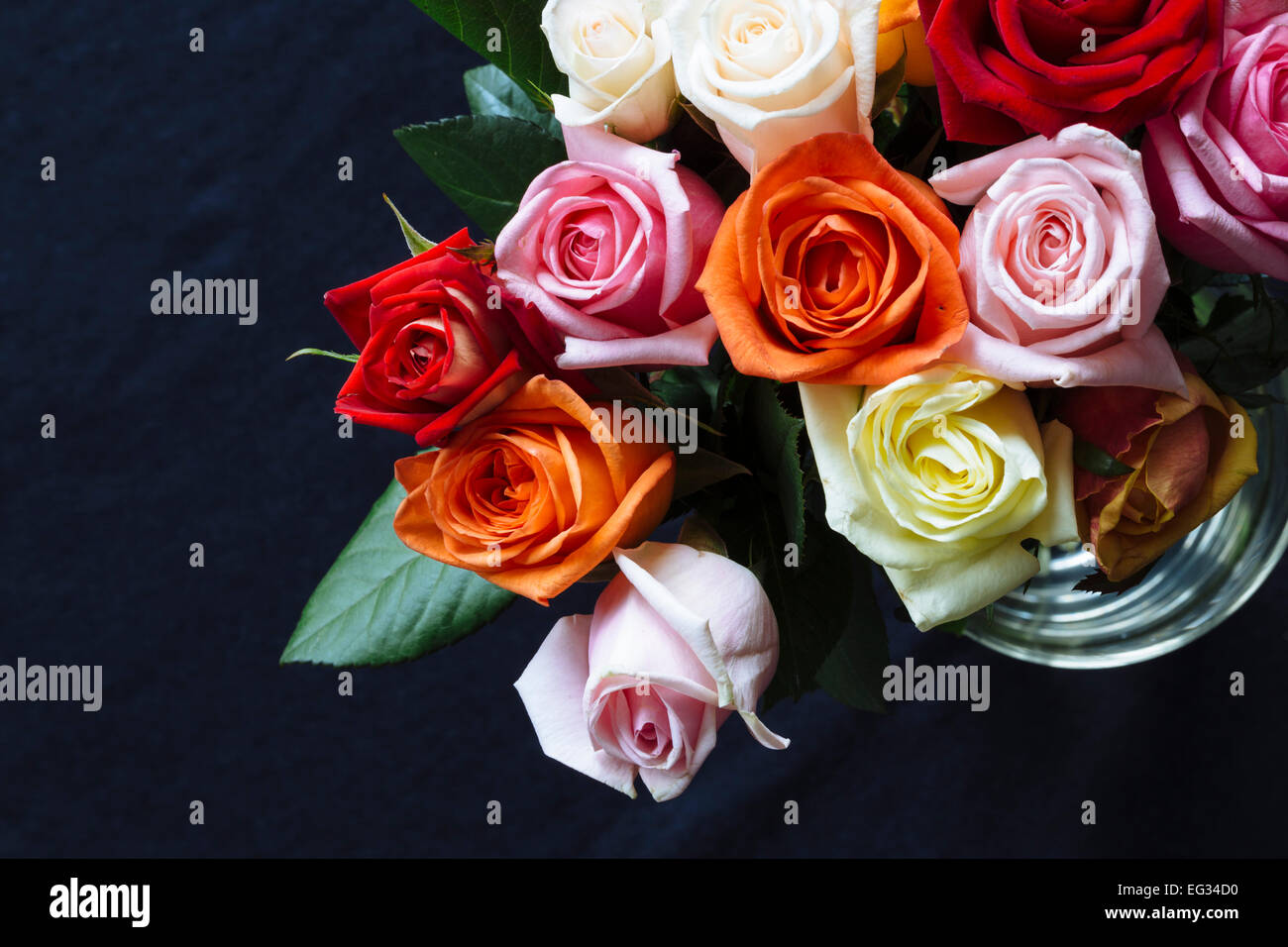 Bunch of colourful roses in vase against dark surface Stock Photo - Alamy