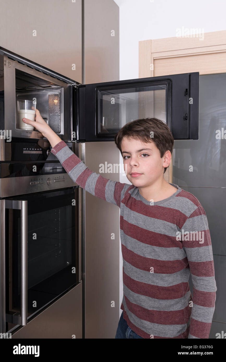 Young boy warming a glass of milk in the microwave Stock Photo - Alamy