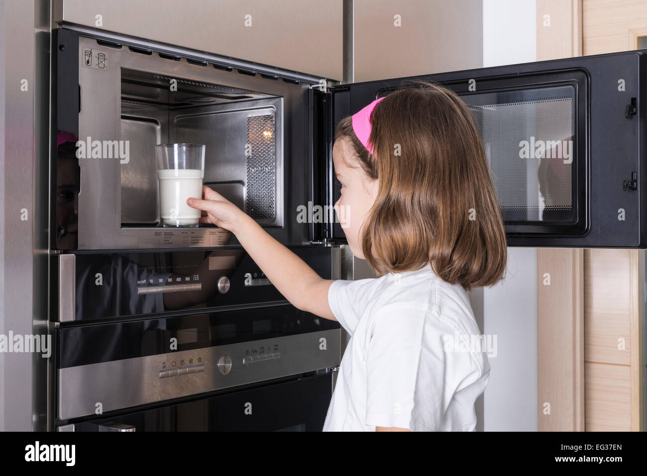 Little girl warming a glass of milk in the microwave Stock Photo - Alamy