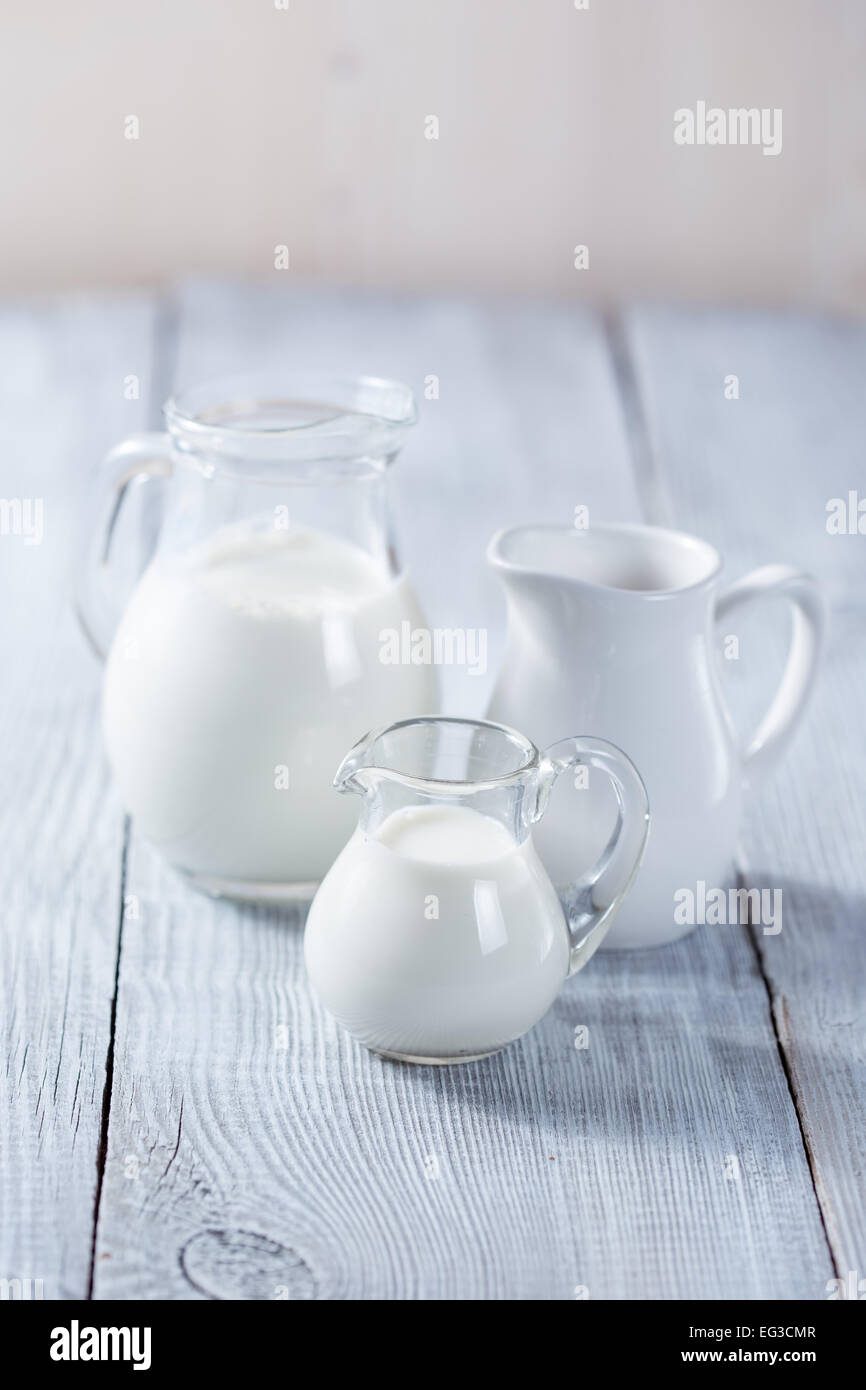 Three milk jars on white wooden background Stock Photo - Alamy