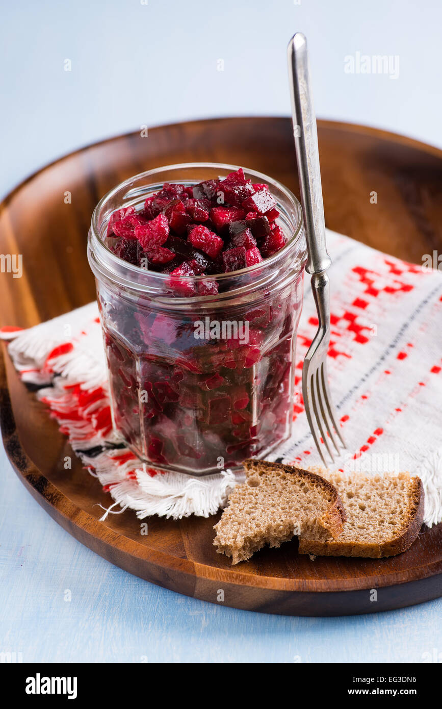 Russian beetroot salad in glass jar over wooden tray, fork and rye ...