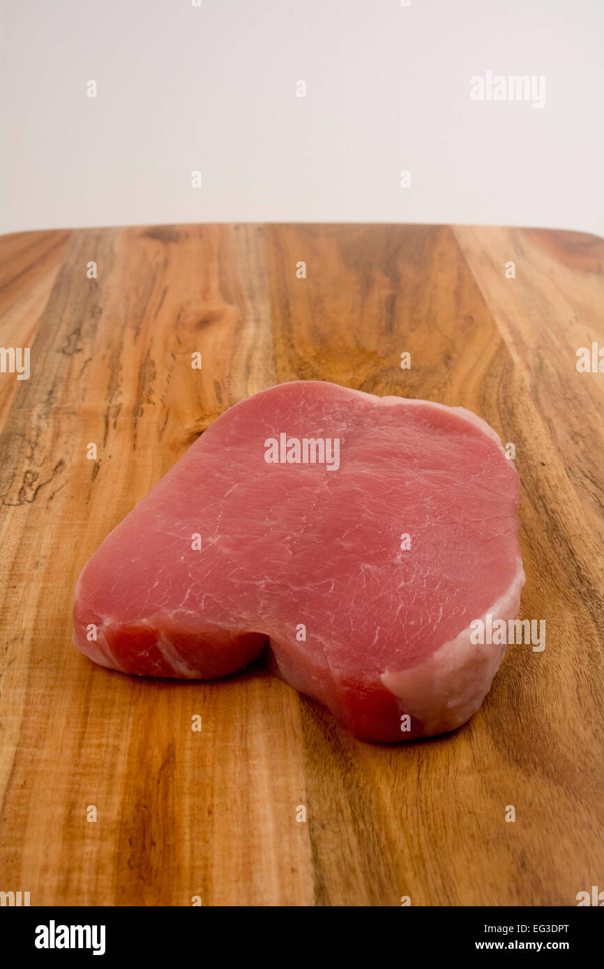 A raw pork chop on a cutting board in the studio Stock Photo - Alamy