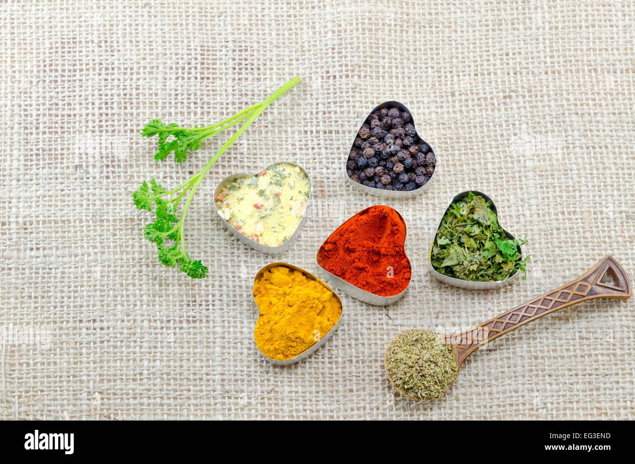 Various spices in heart shaped containers on a tablecloth decorated ...