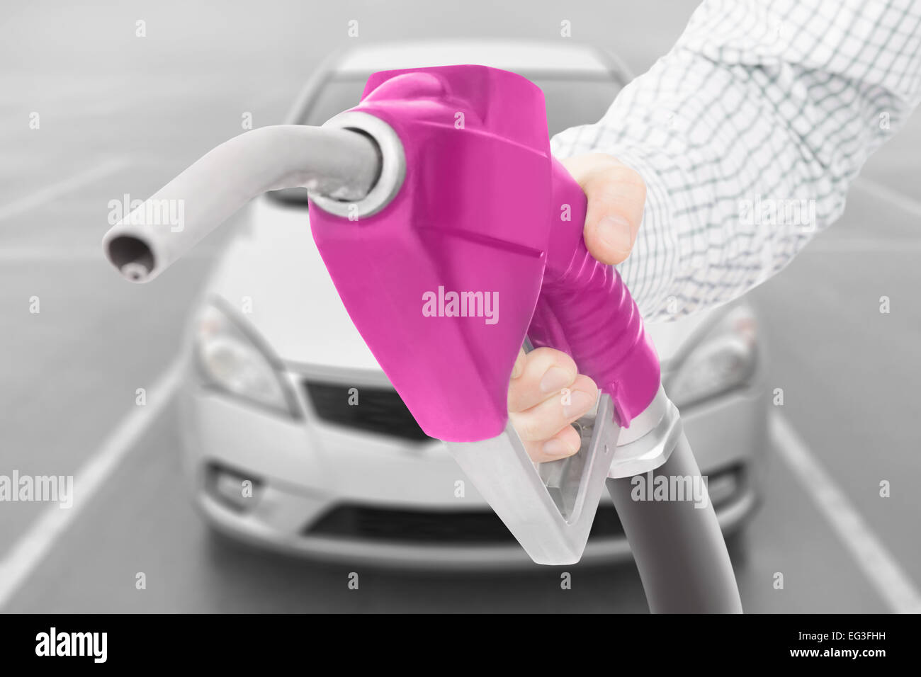 Pink color fuel pump gun in hand with car on background Stock Photo - Alamy