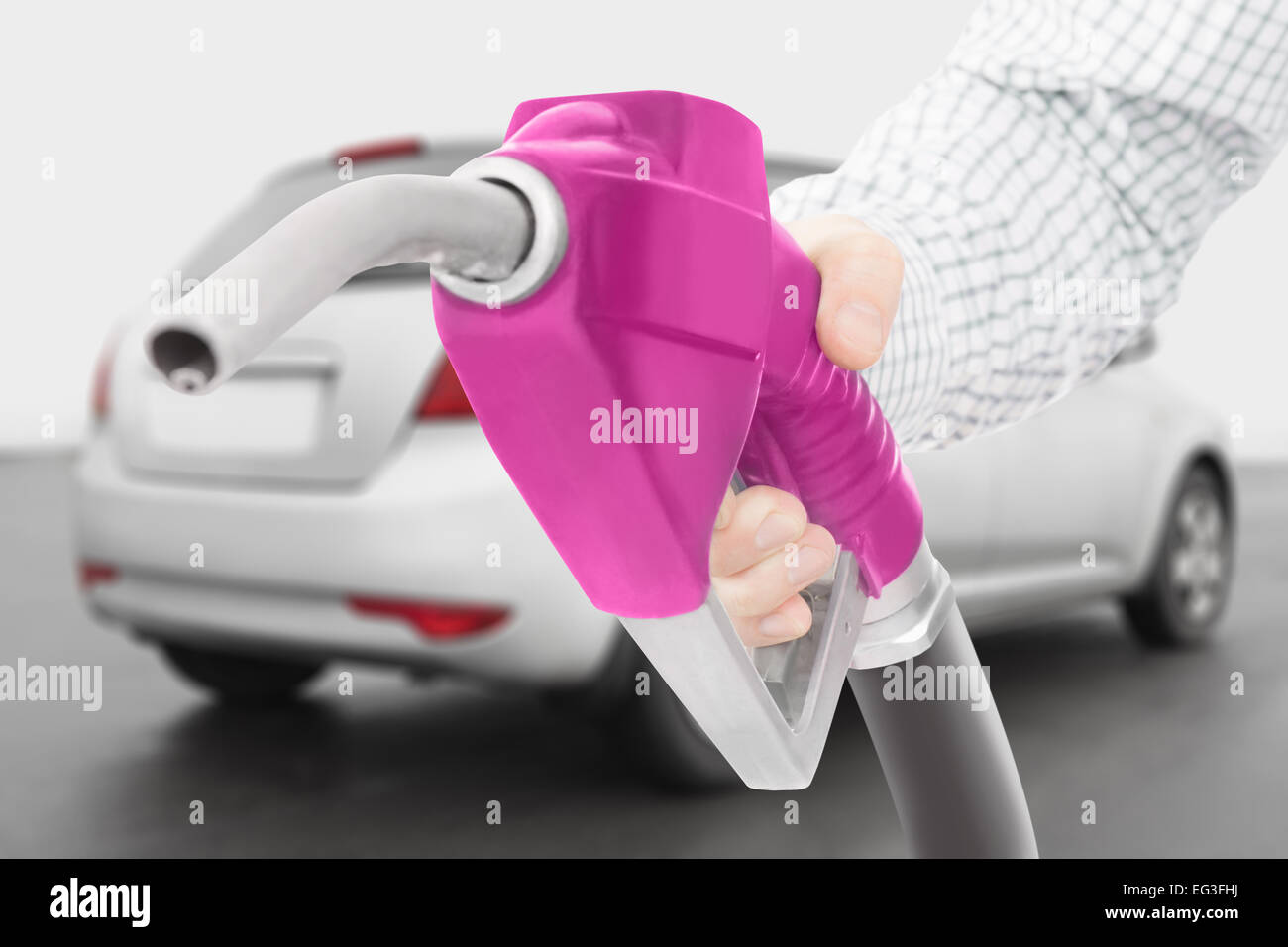 Pink color fuel pump gun in hand with car on background Stock Photo - Alamy