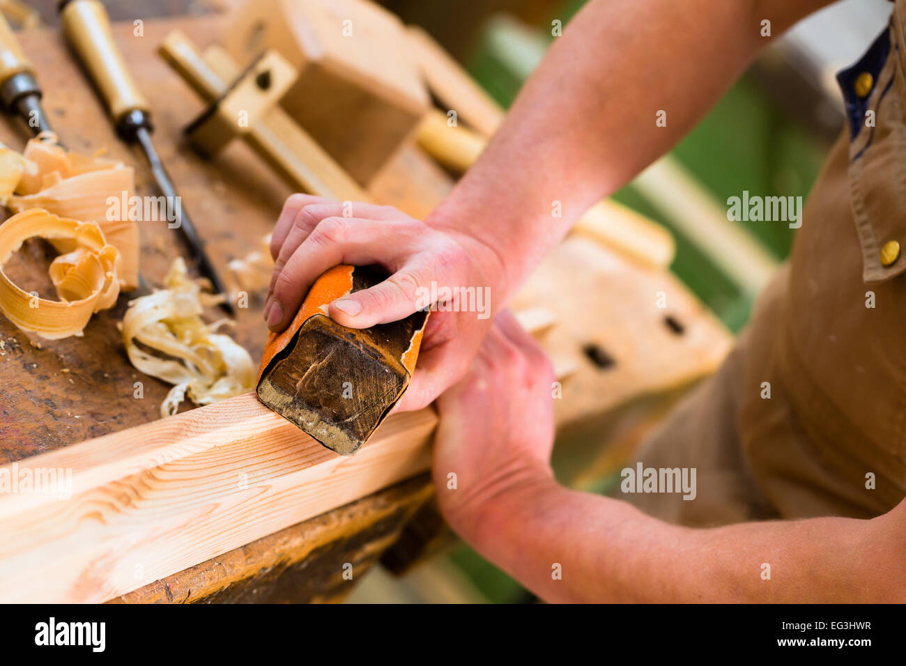Carpenter working with a sanding block and sandpaper in his workshop ...