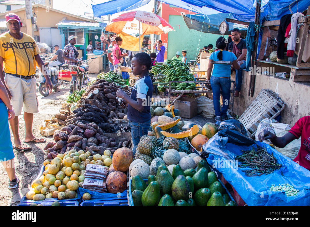 A young street vendor sells his wares in the market in Higuey ...