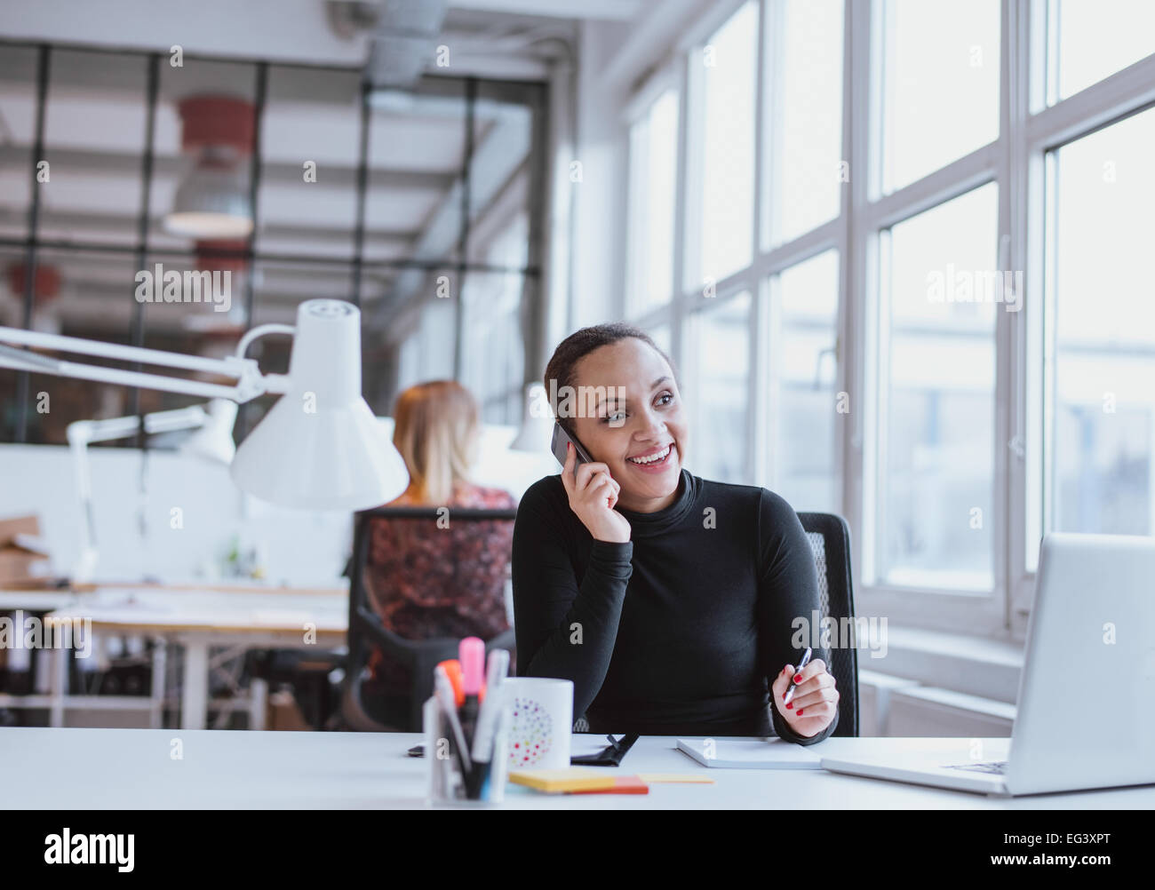 Young african woman using mobile phone while at work. Female executive ...
