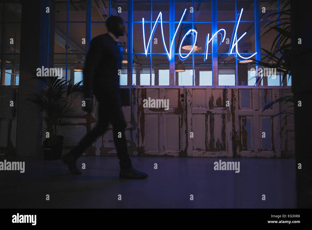 Corridor of modern office with young man walking by. Big neon light ...