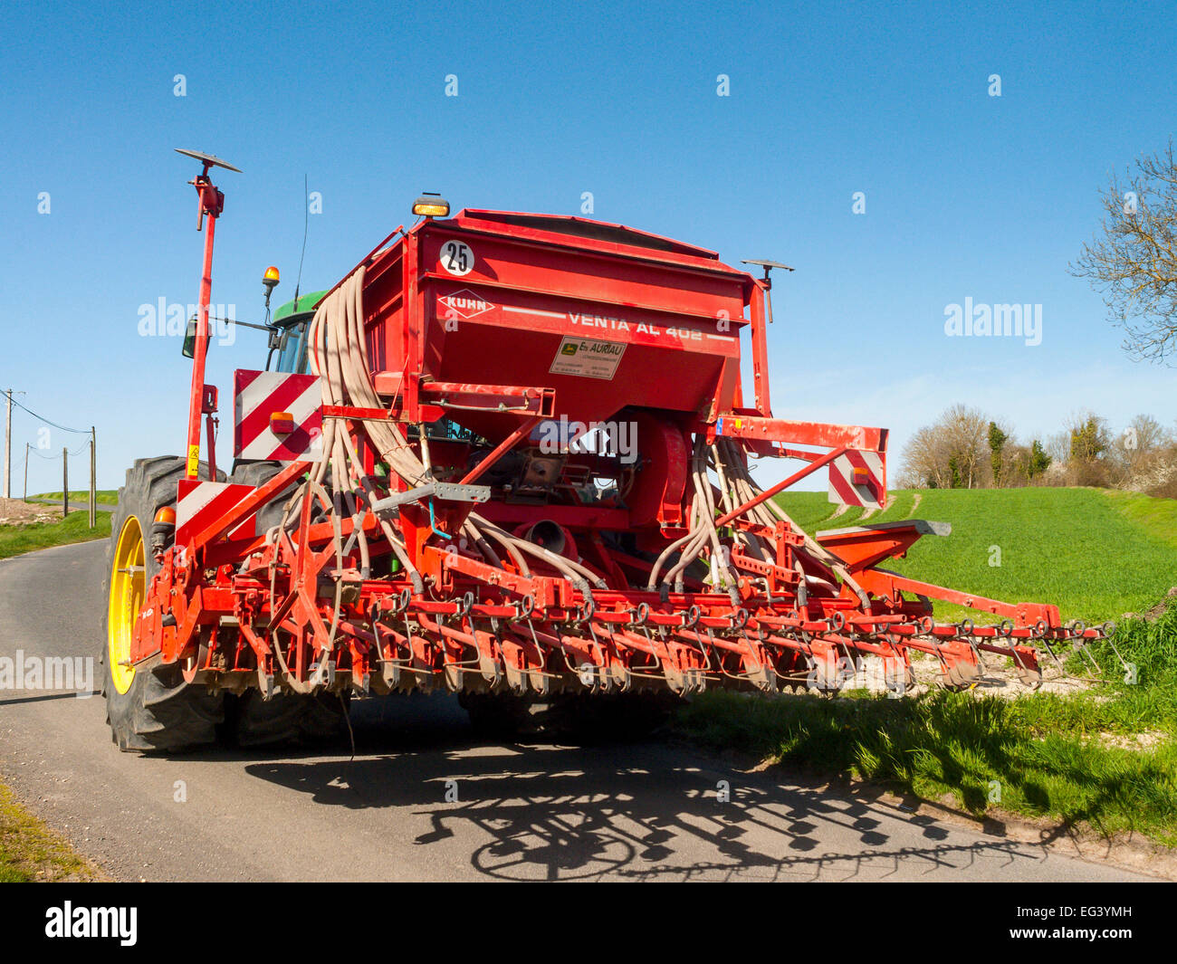 Wide tractor and seeding machine negotiating narrow country road ...