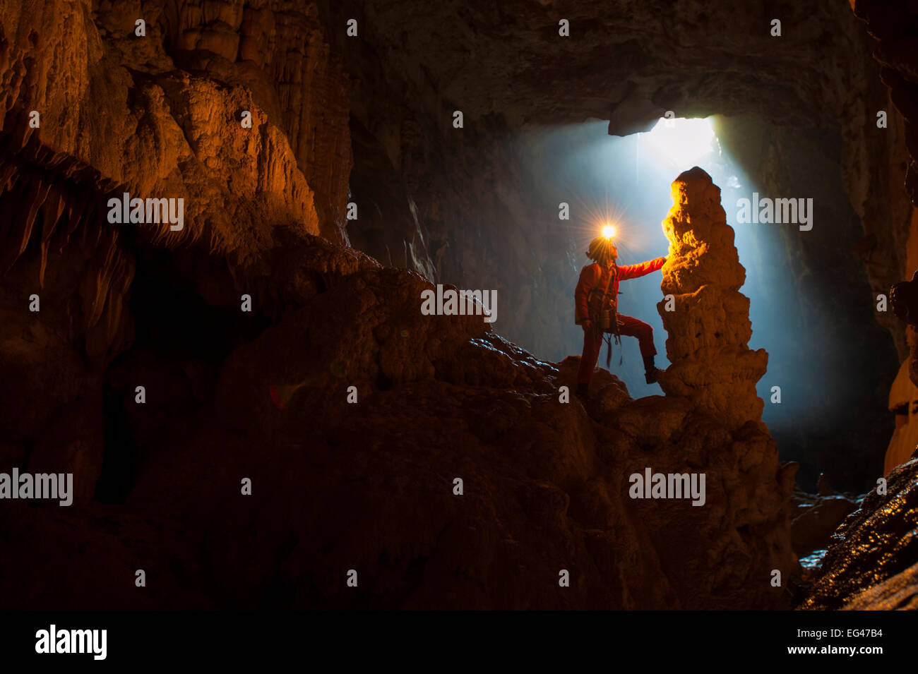 Potholer touching stalagmite whilst exploring the Graller del Boixaguer ...