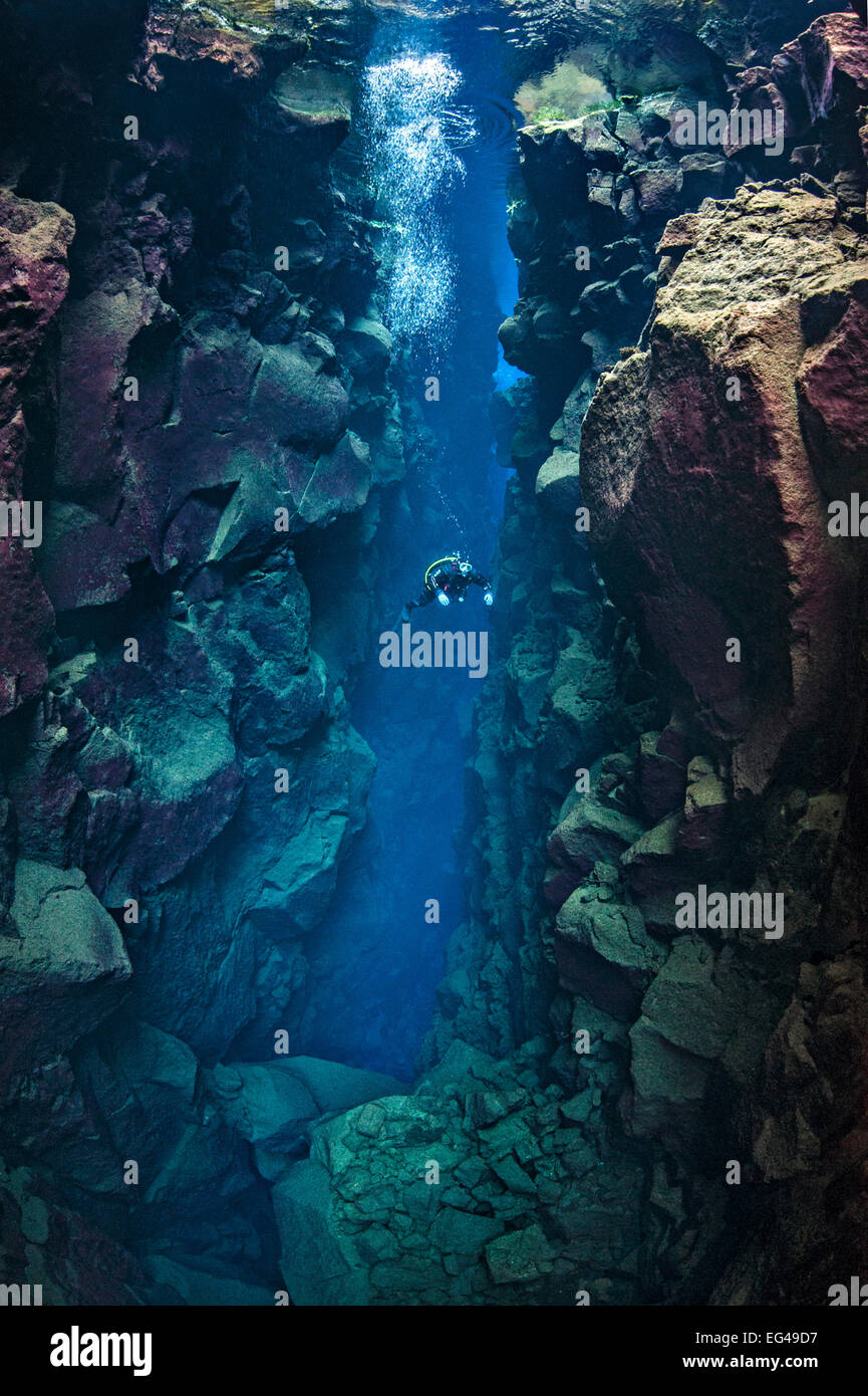 A diver explores Nikulasargj Canyona deep fault filled fresh water in ...