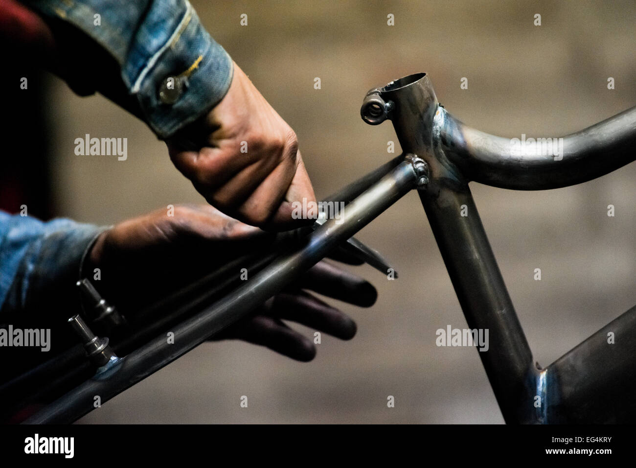 A bicycle worker grinds a recently welded bike frame in a small scale ...
