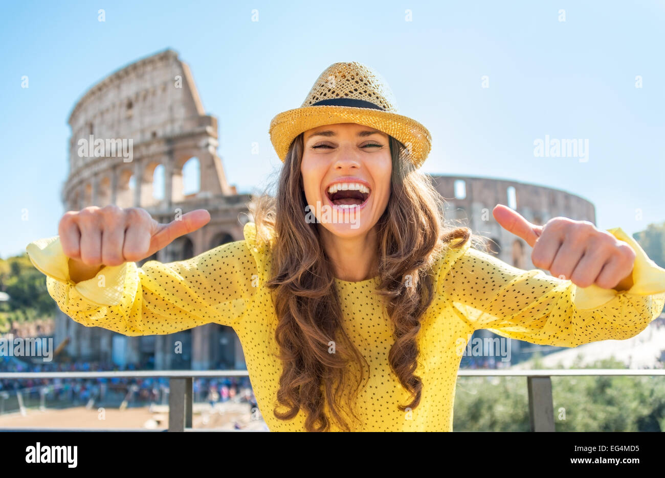 Young woman showing thumbs up in front of colosseum in rome, italy ...