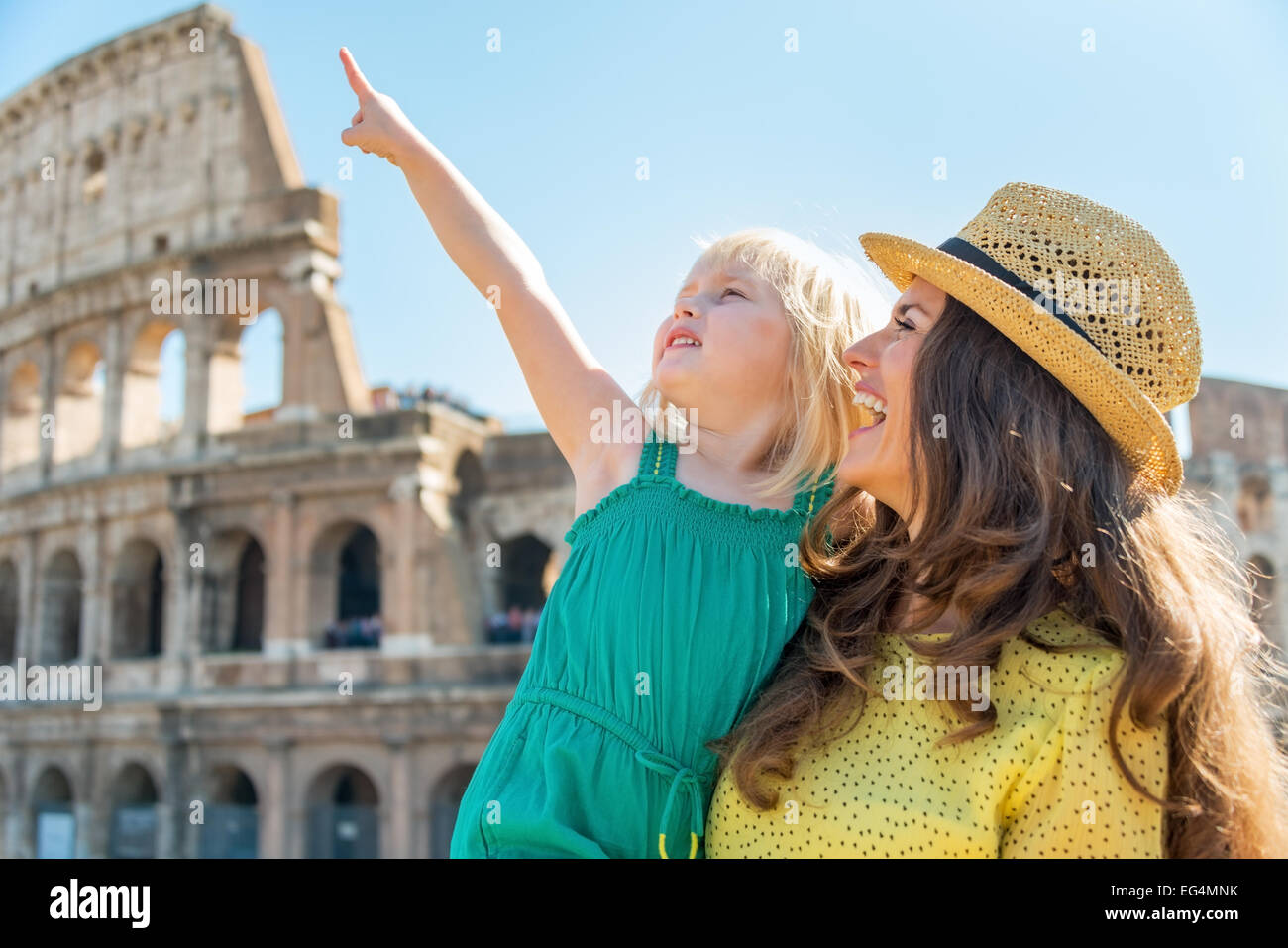 Happy mother and baby girl pointing in front of colosseum in rome ...