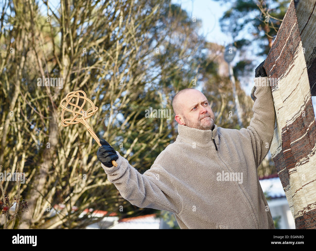 Homeworks, a man and the carpet beater Stock Photo - Alamy