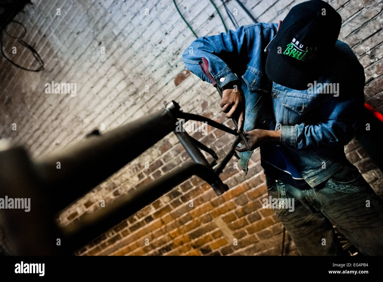 A bicycle worker grinds a recently welded bike frame in a small scale ...
