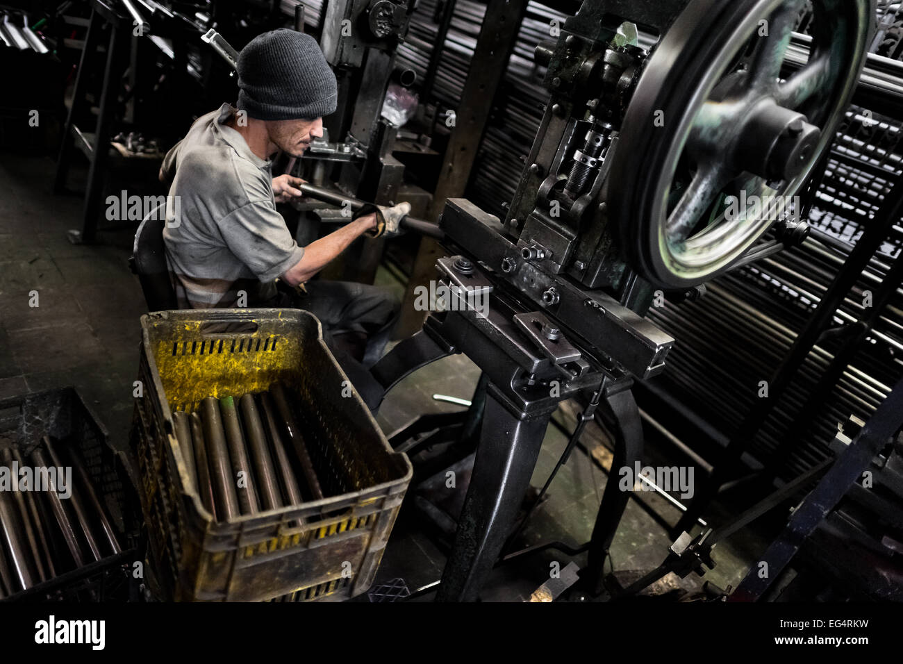 A bicycle worker works on a tube bender machine in a small scale ...