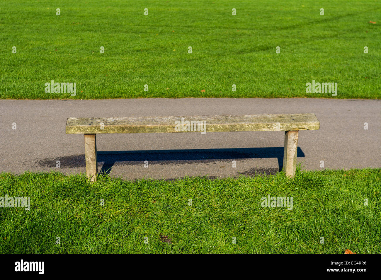 Empty park bench, shadow, path and green grass Stock Photo - Alamy