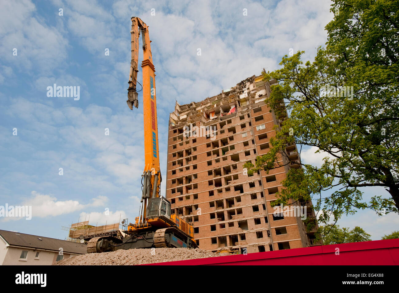 A demolition crane sits in front of a partially demolished tower block ...