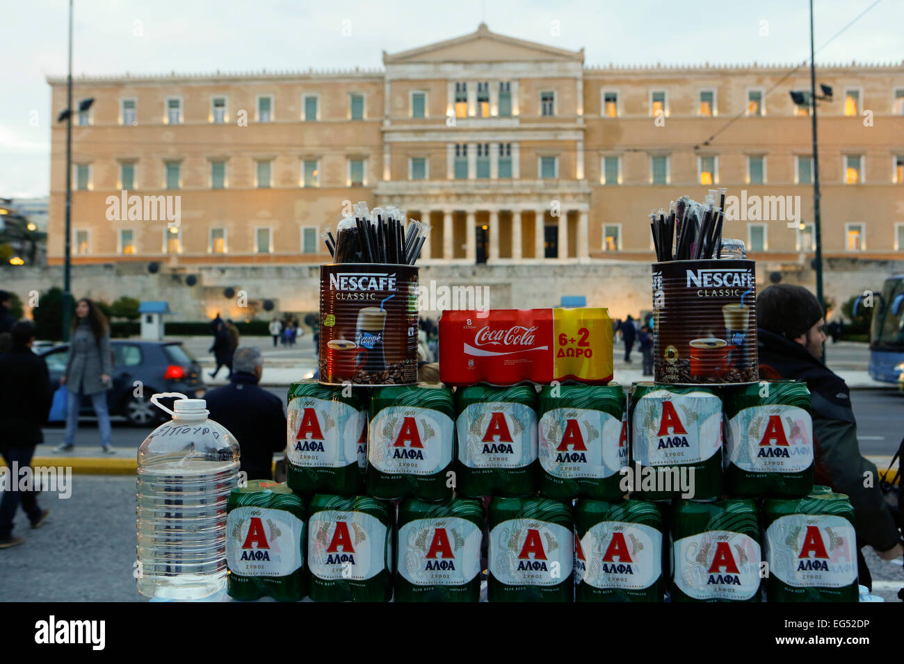 A vendor with drinks stands outside the Greek Parliament, selling beer ...