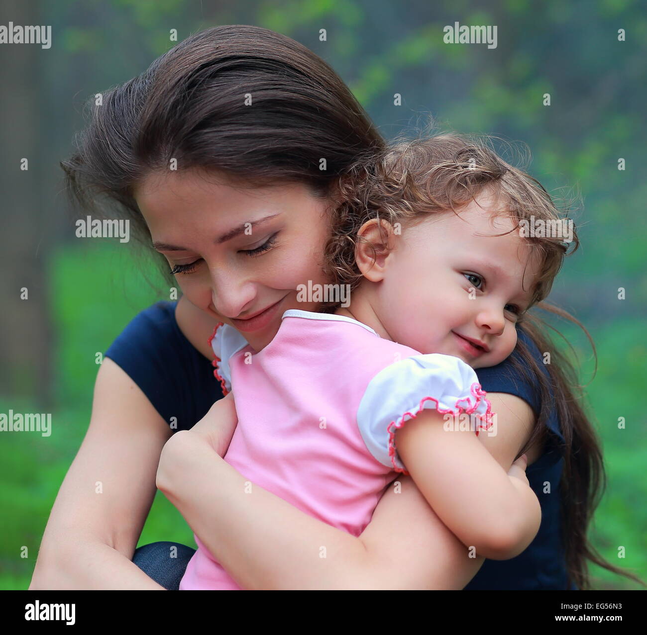 Smiling happy mother and cute kid girl cuddling outdoor summer ...