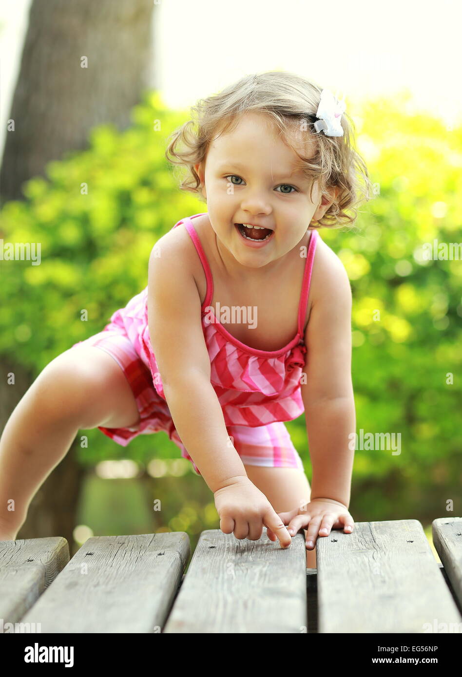 Small smiling child girl climbing and looking happy on summer ...