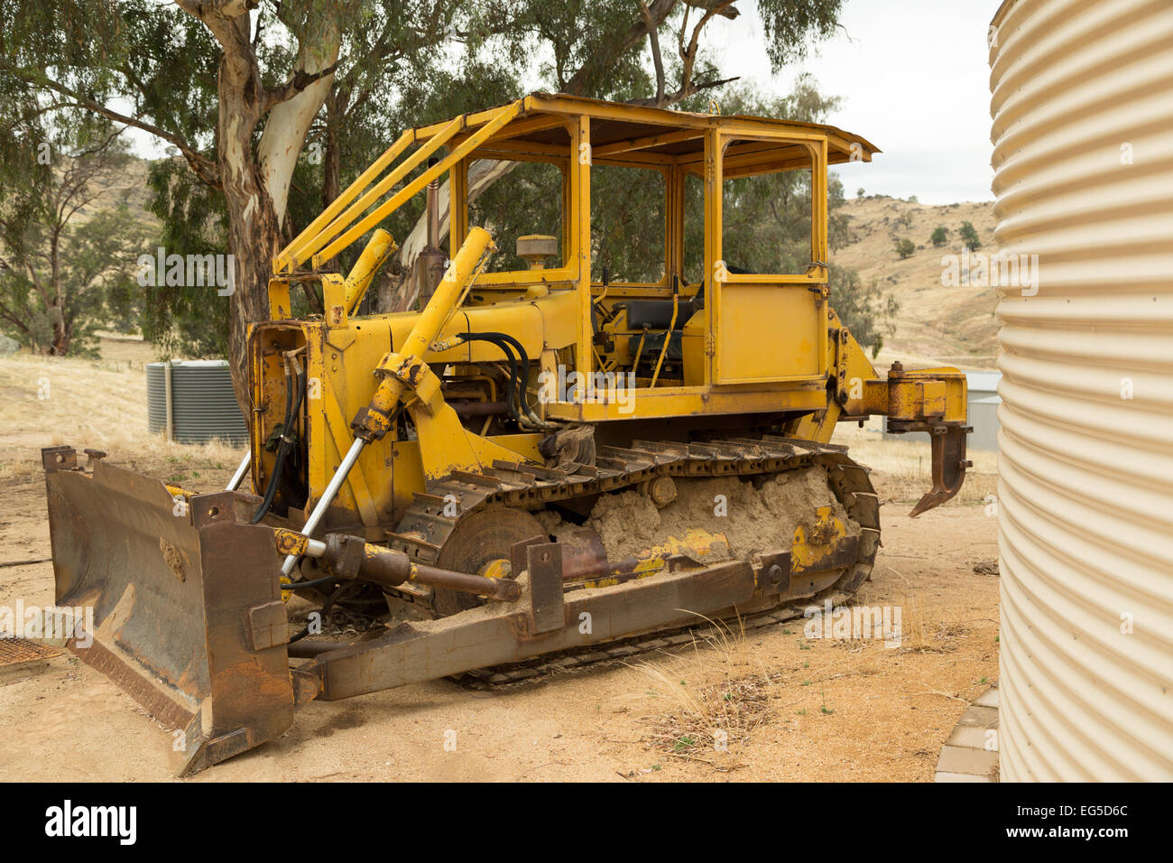 A photograph of a tough looking old bulldozer next to a water tank on ...