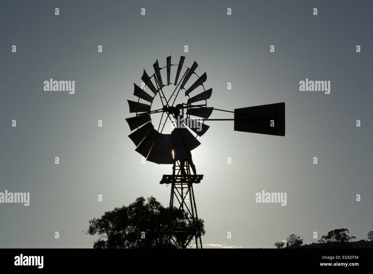 A silhouetted photograph of a farmer climbing a windmill to repair it ...