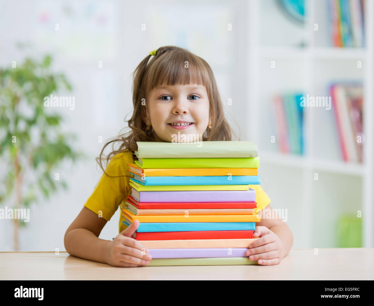 Happy kid girl with a stack of books Stock Photo - Alamy