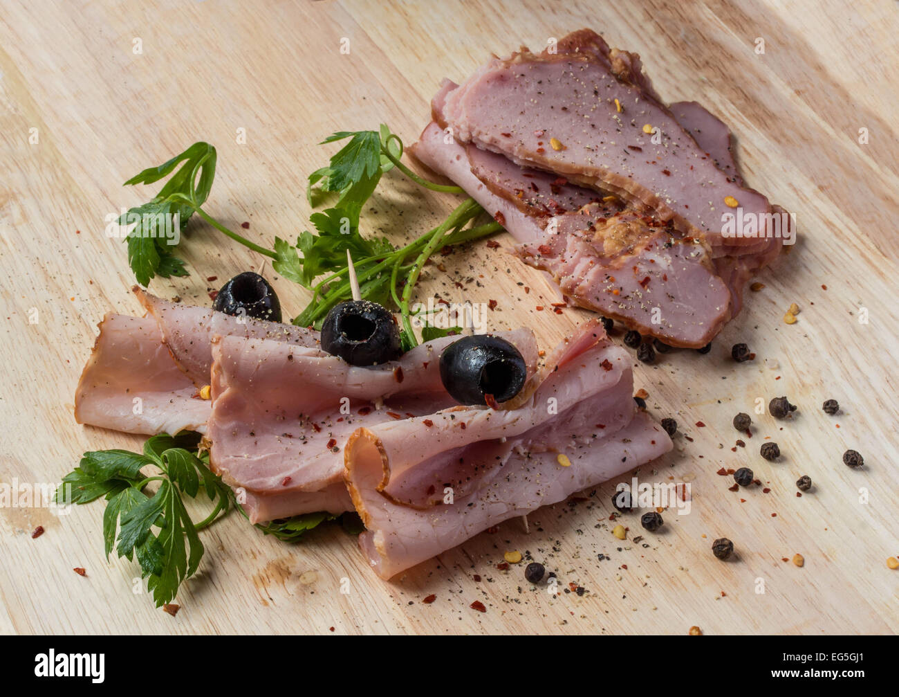 Ham pieces with black olives and spices Stock Photo - Alamy