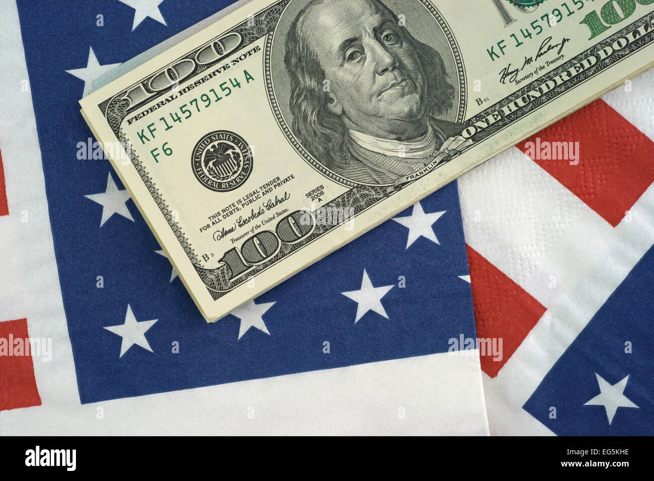 Several hundred dollar American bills atop red white and blue flag ...