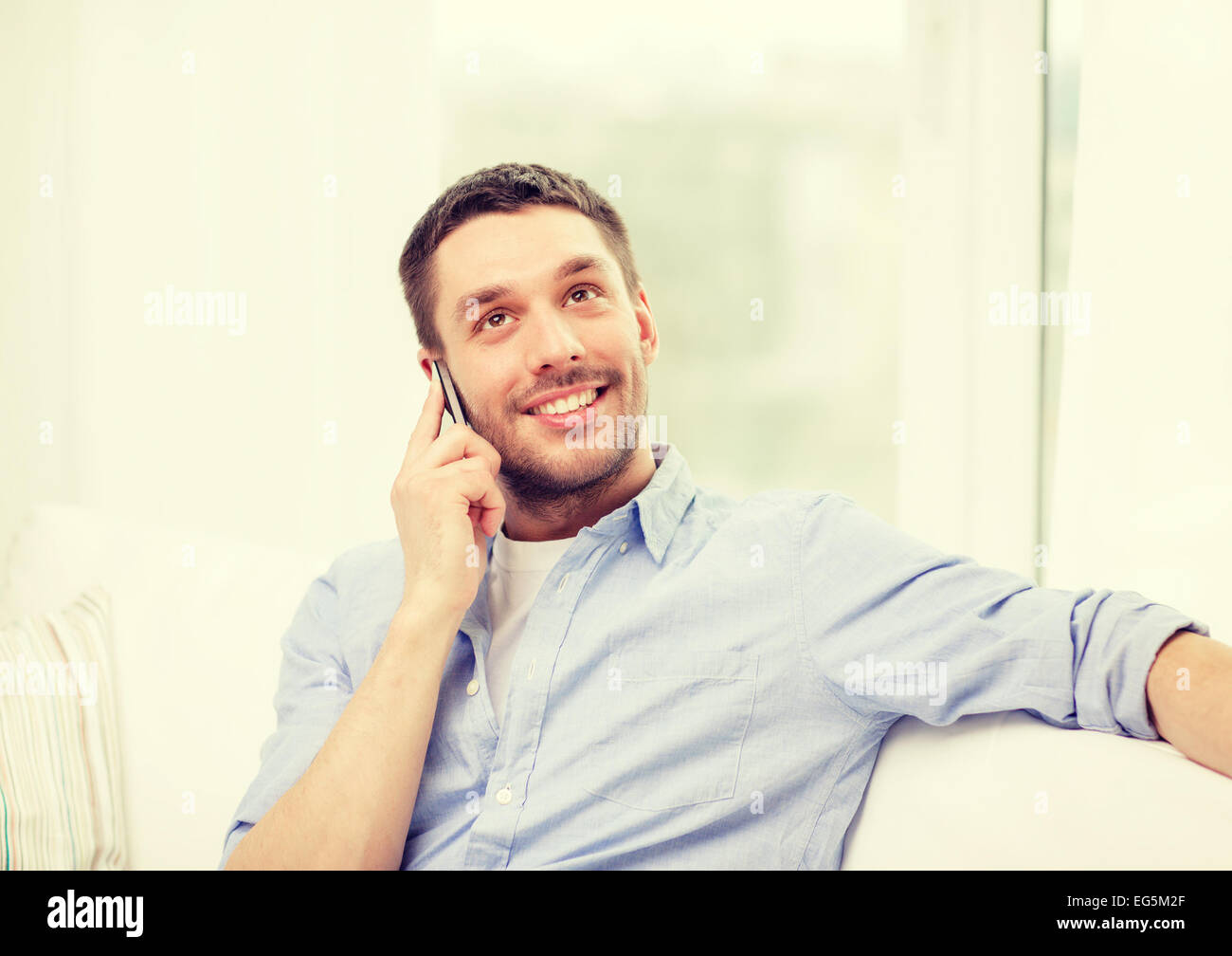 smiling man with smartphone at home Stock Photo - Alamy