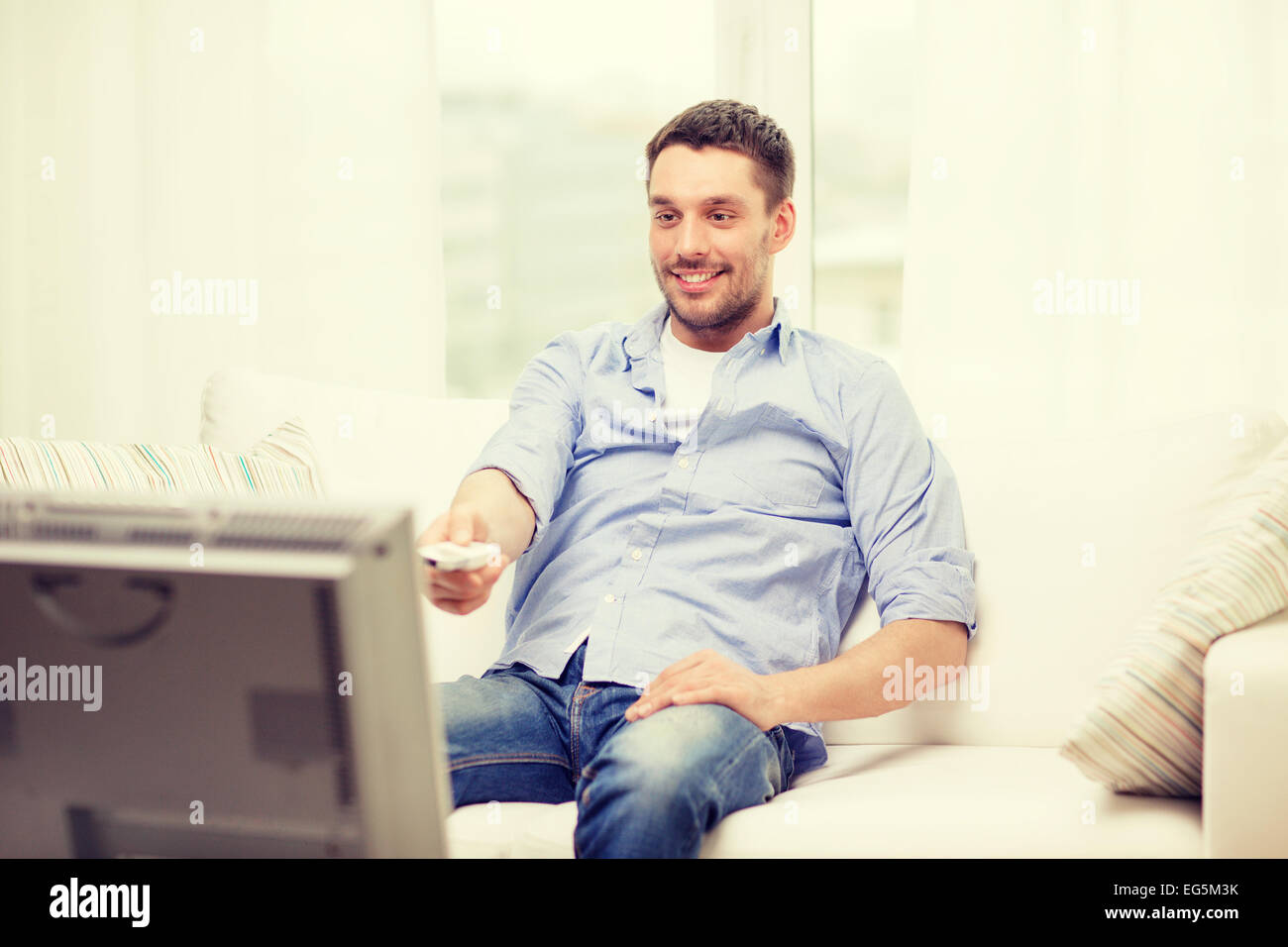 smiling man with tv remote control at home Stock Photo - Alamy
