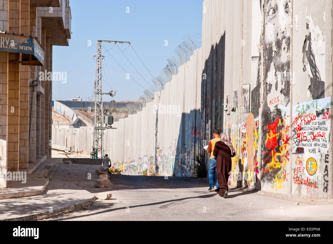 Young people go along the Israel-built separation wall that separates ...