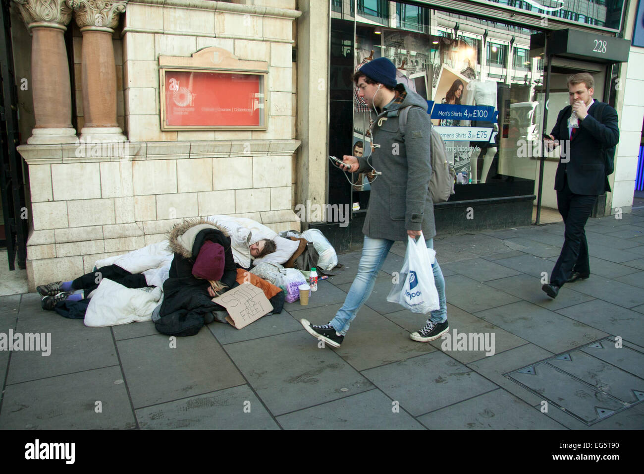 London,UK. 17th February 2015. Pedestrians walk past homeless people ...